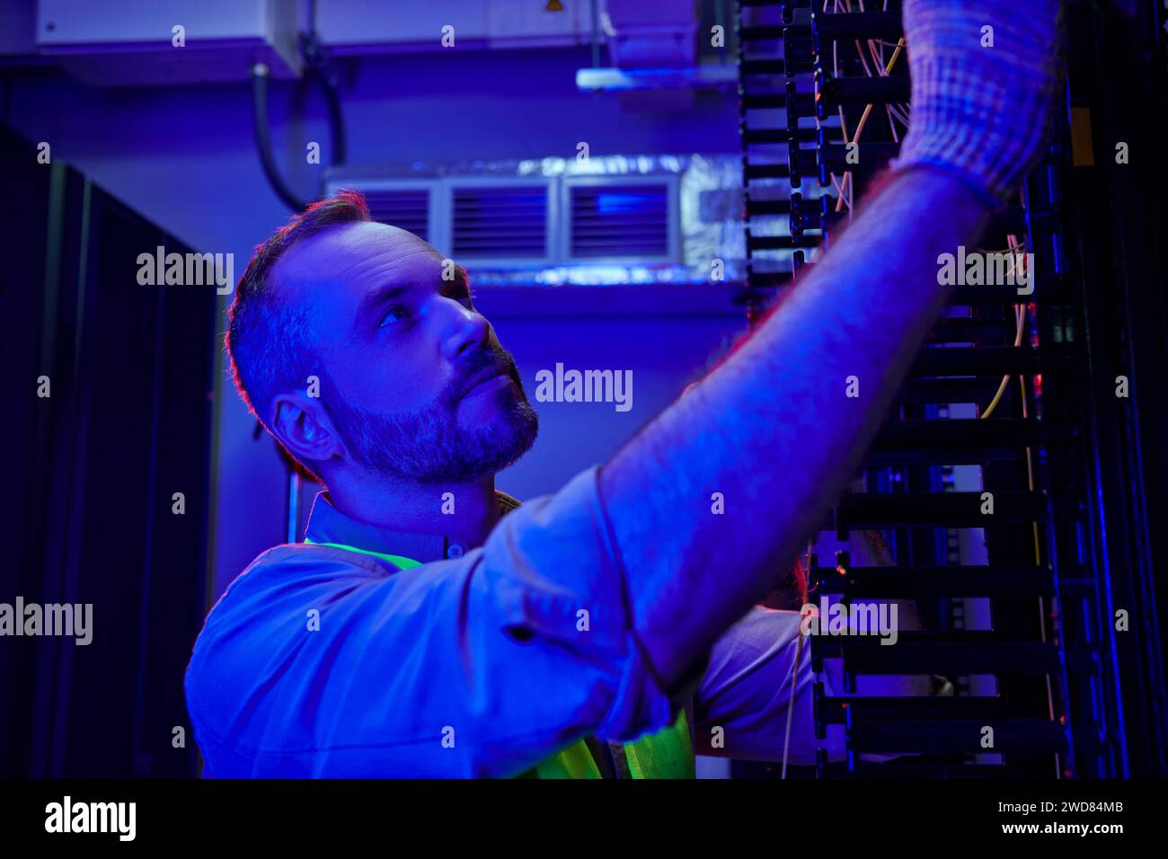 good looking cheerful professional in safety vest and gloves inspecting ...