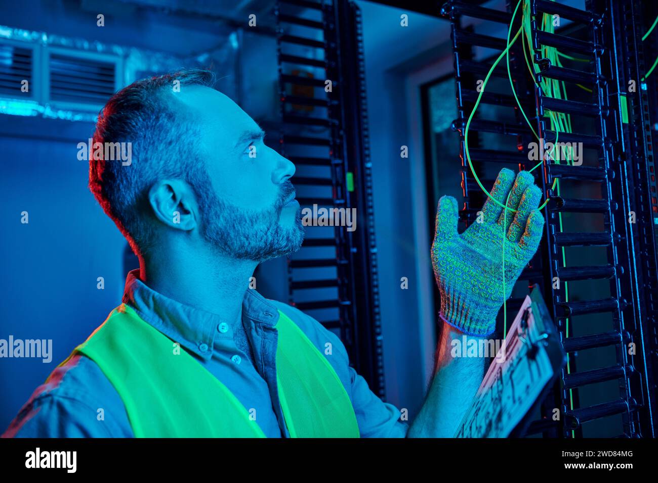 hardworking professional in safety vest and gloves inspecting cable and ...