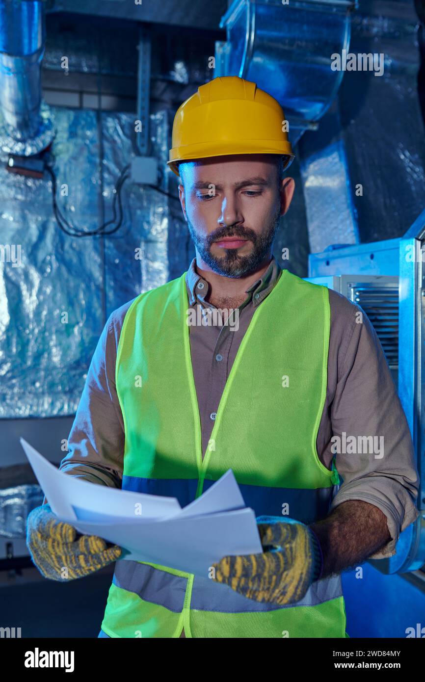 good looking dedicated professional in helmet looking attentively at ...