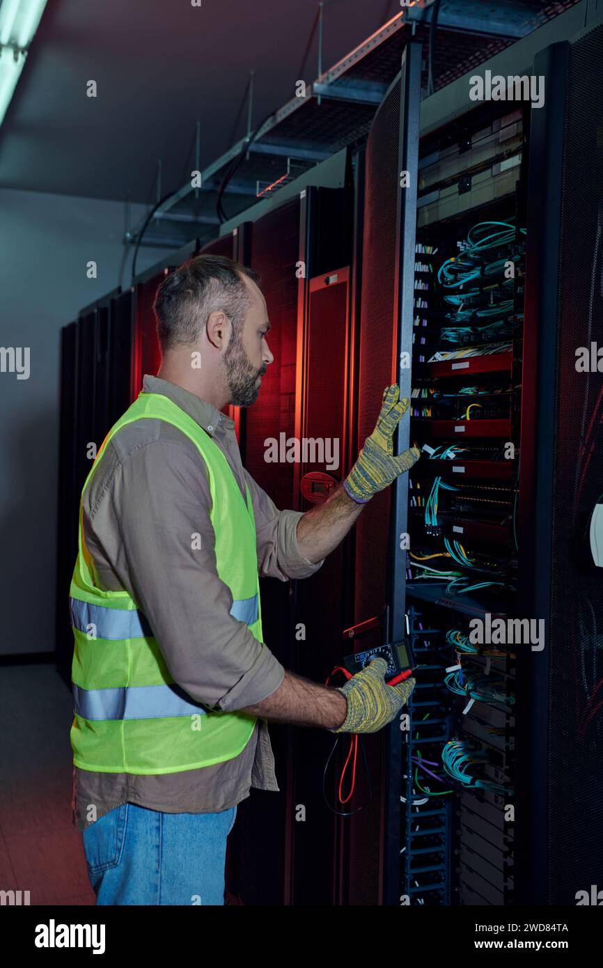 good looking technician in safety vest and gloves holding detector in ...