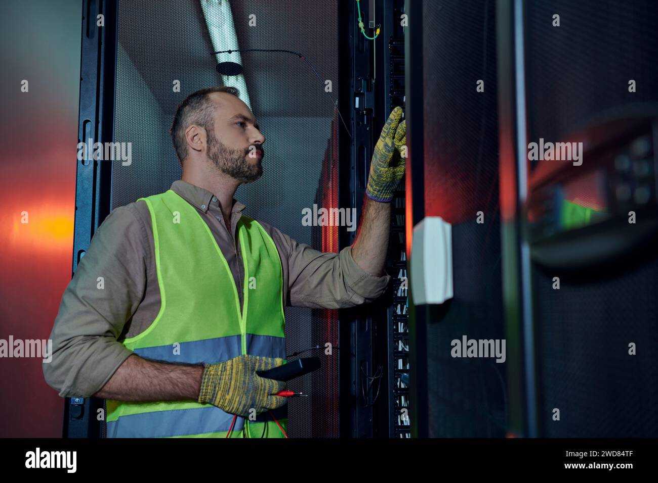 pensive specialist in safety vest and gloves using detector during ...