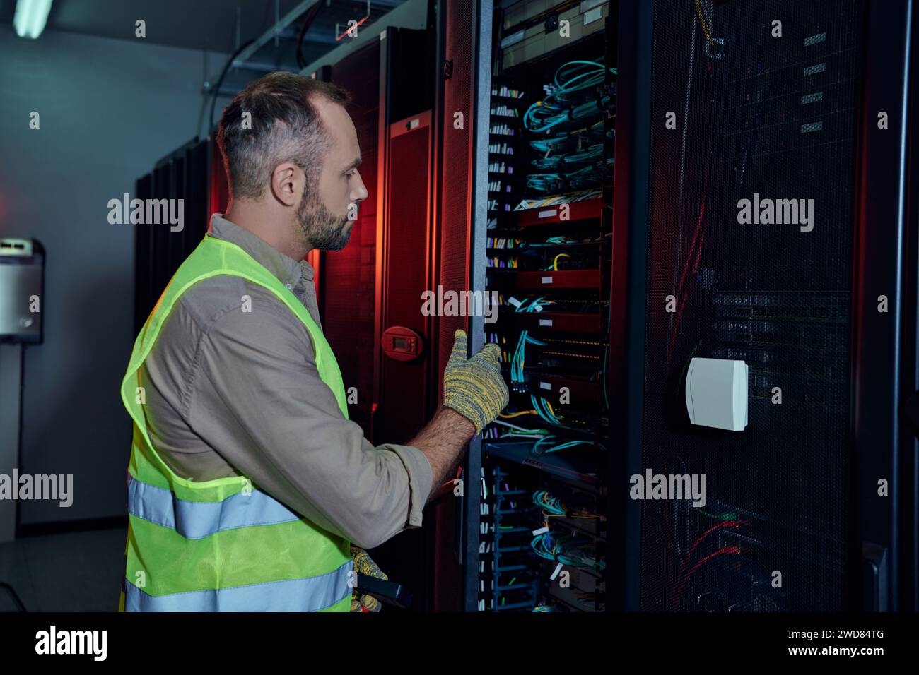good looking professional in safety gloves and vest inspecting ...