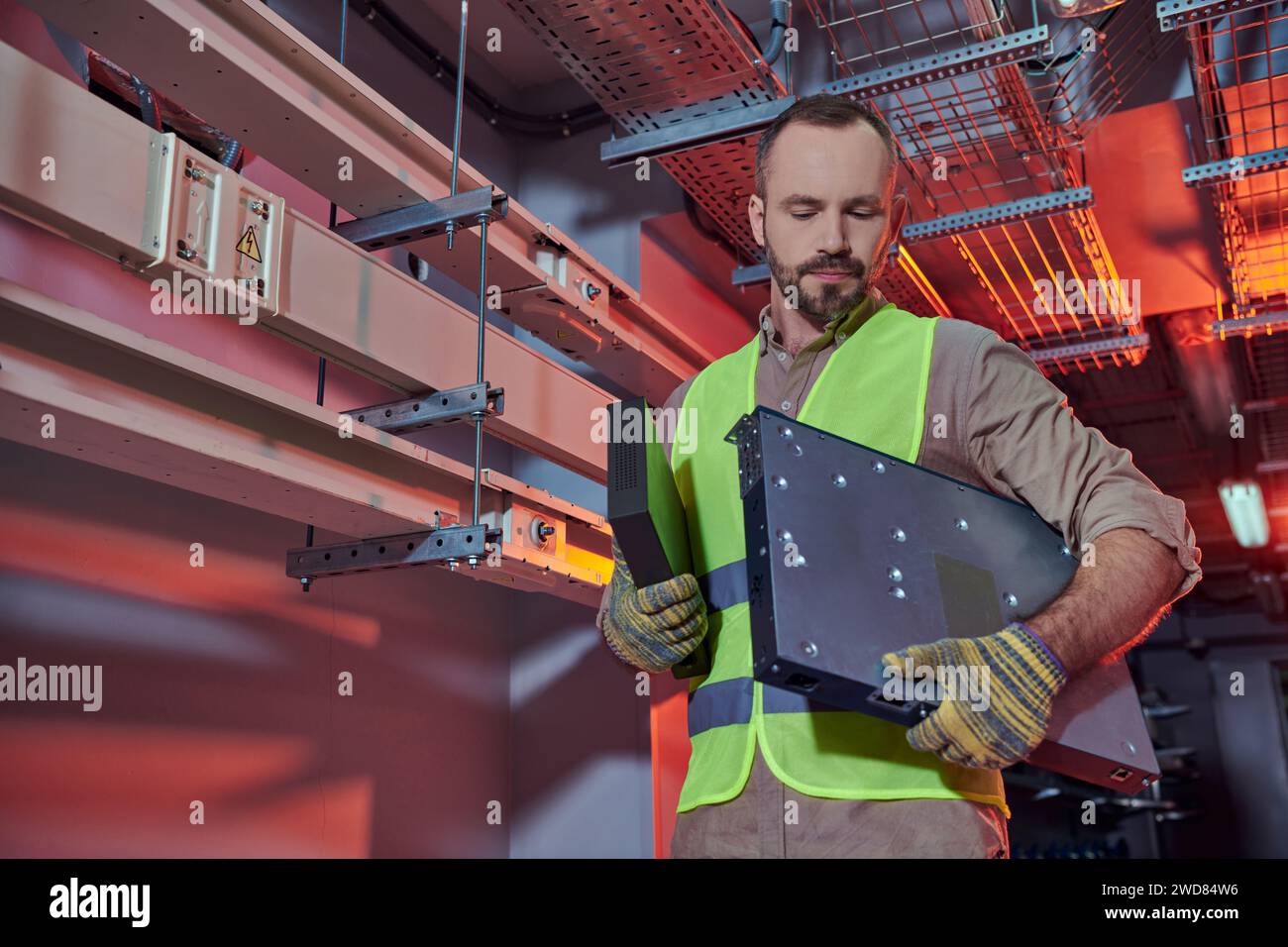 attractive concentrated technician in safety vest and gloves working ...