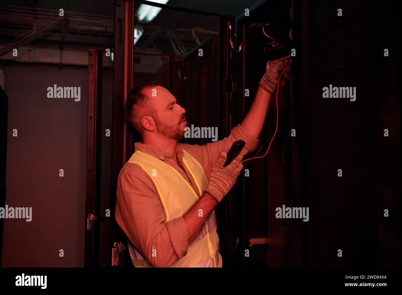 concentrated devoted technician in safety vest and gloves using ...