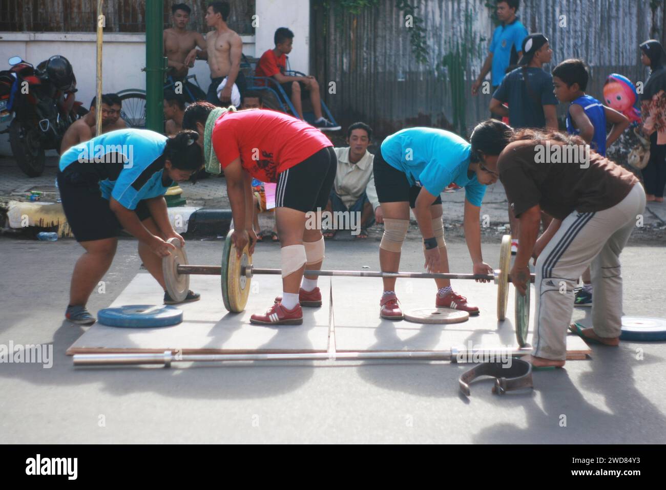 a group of young women are preparing weightlifting equipment on Dhoho ...
