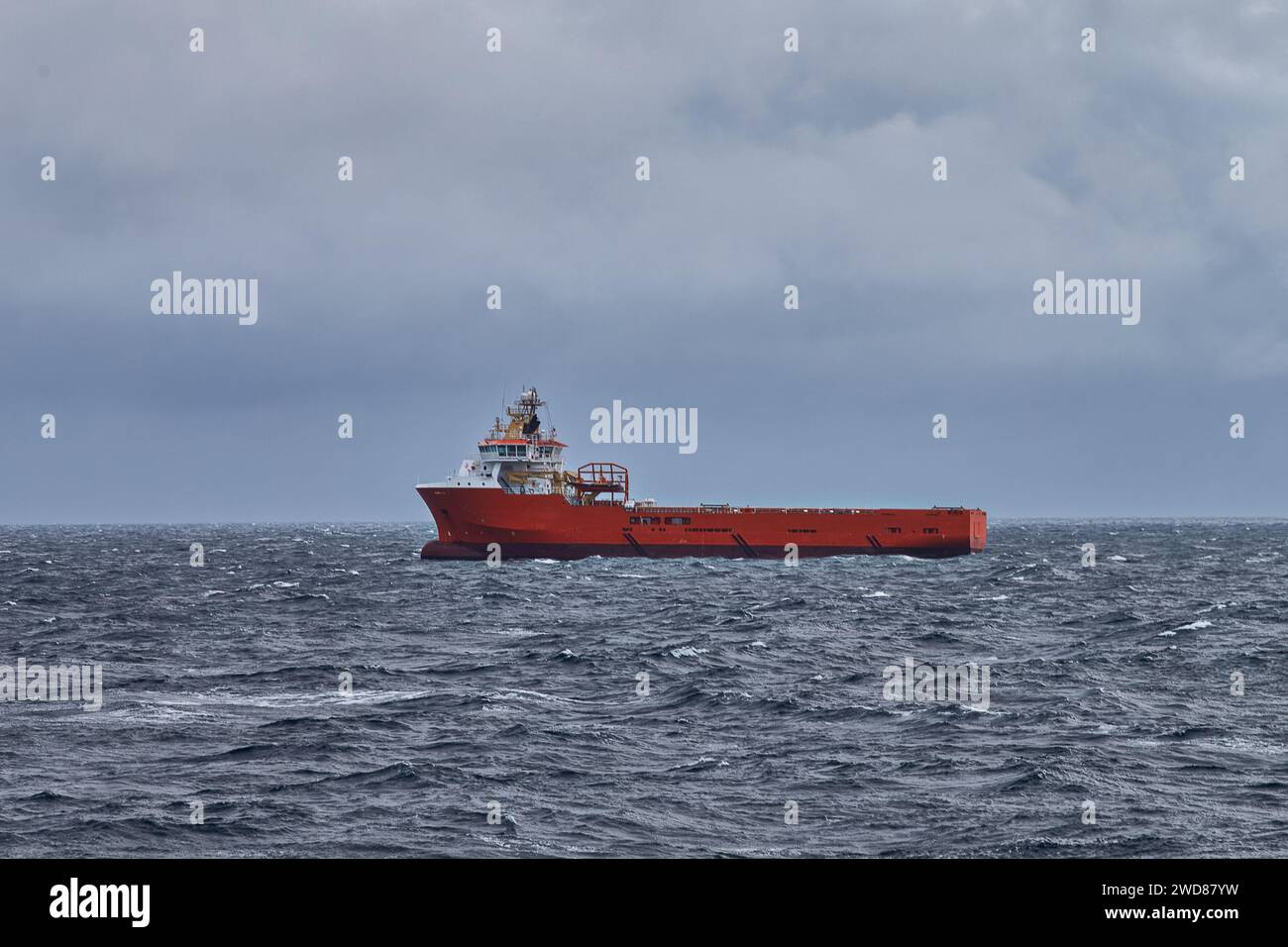 Seascape with red platform supply vessel on the horizon in the grey sea ...