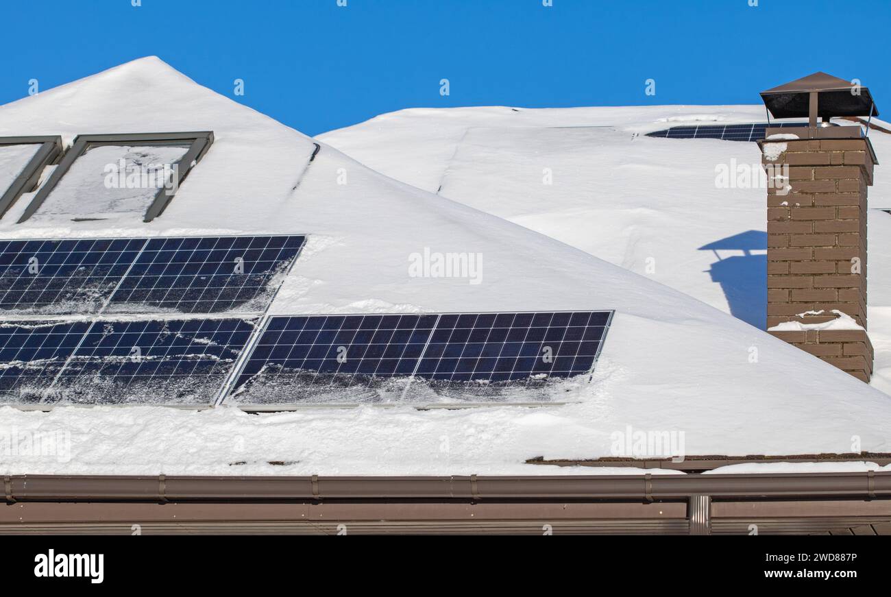 A high-angle shot of a residential rooftop with snow-cleared solar ...
