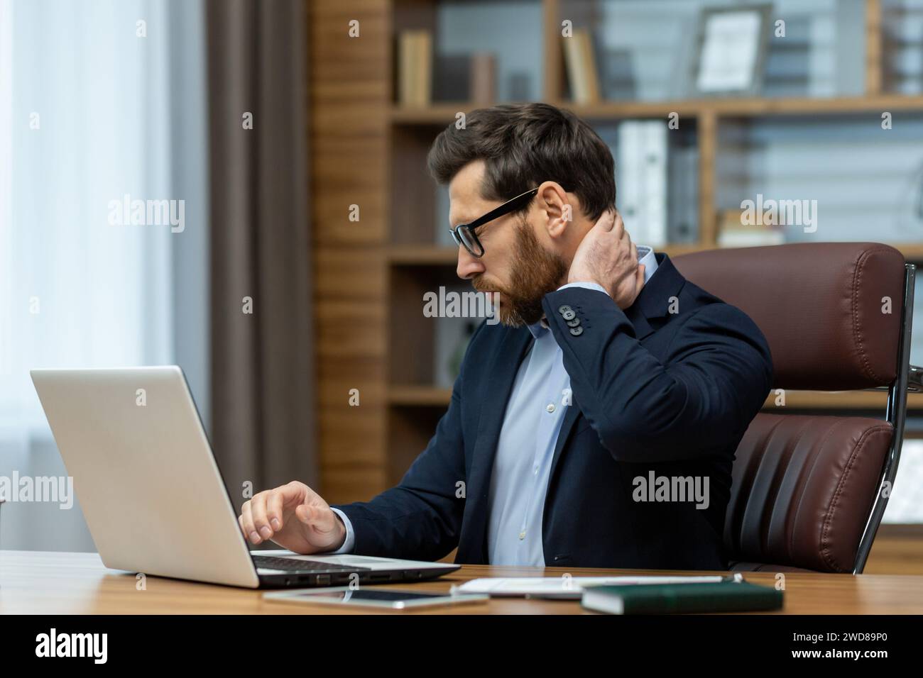Concentrated mature man in business attire working at laptop in a well ...