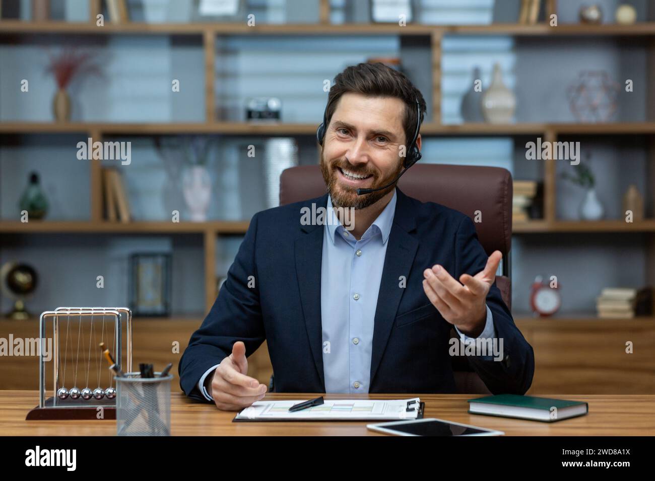 Experienced mature man in a suit and headset working from a well ...