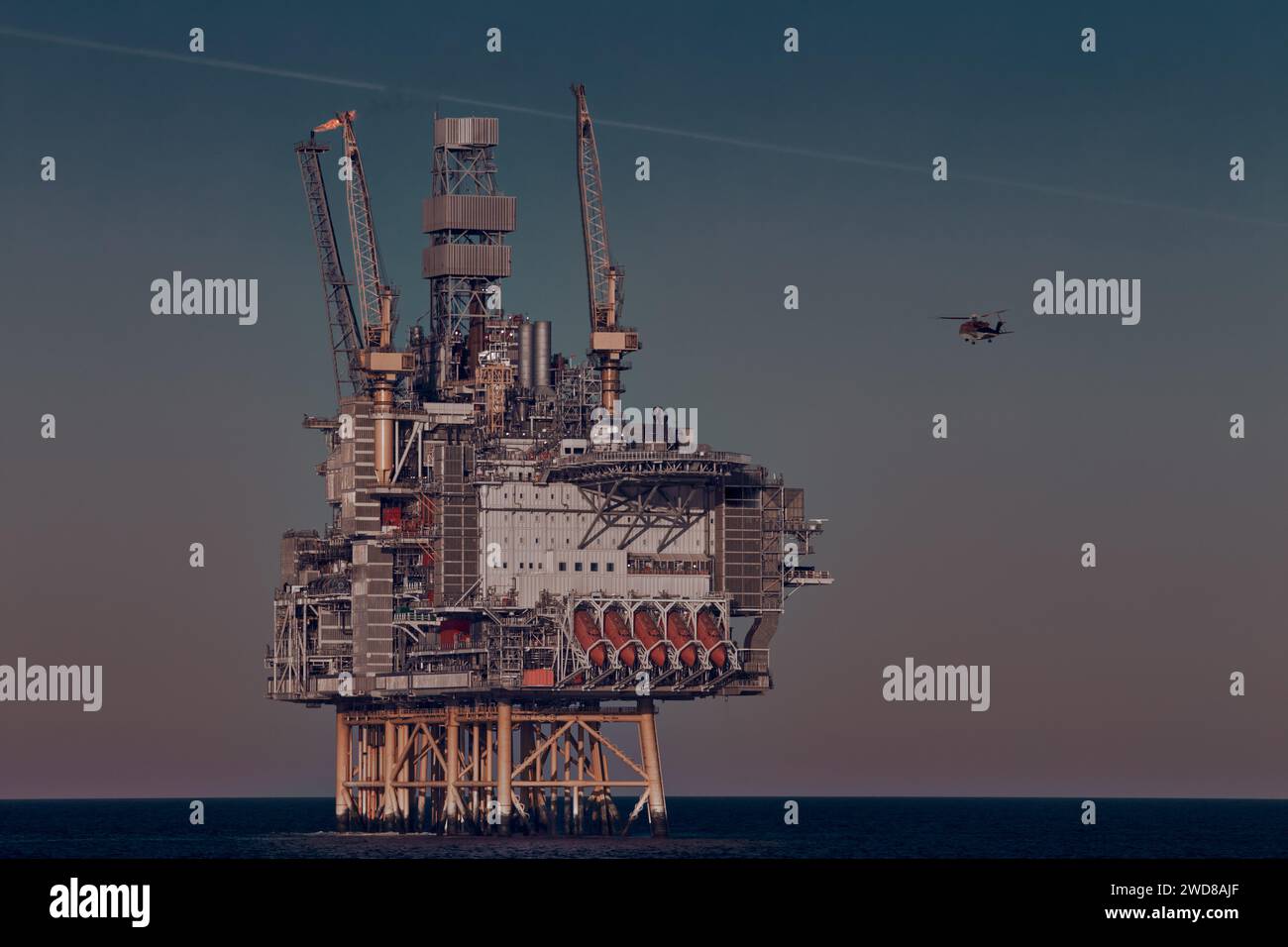 Helicopter flying towards jack up oil rig in the ocean for landing, on ...