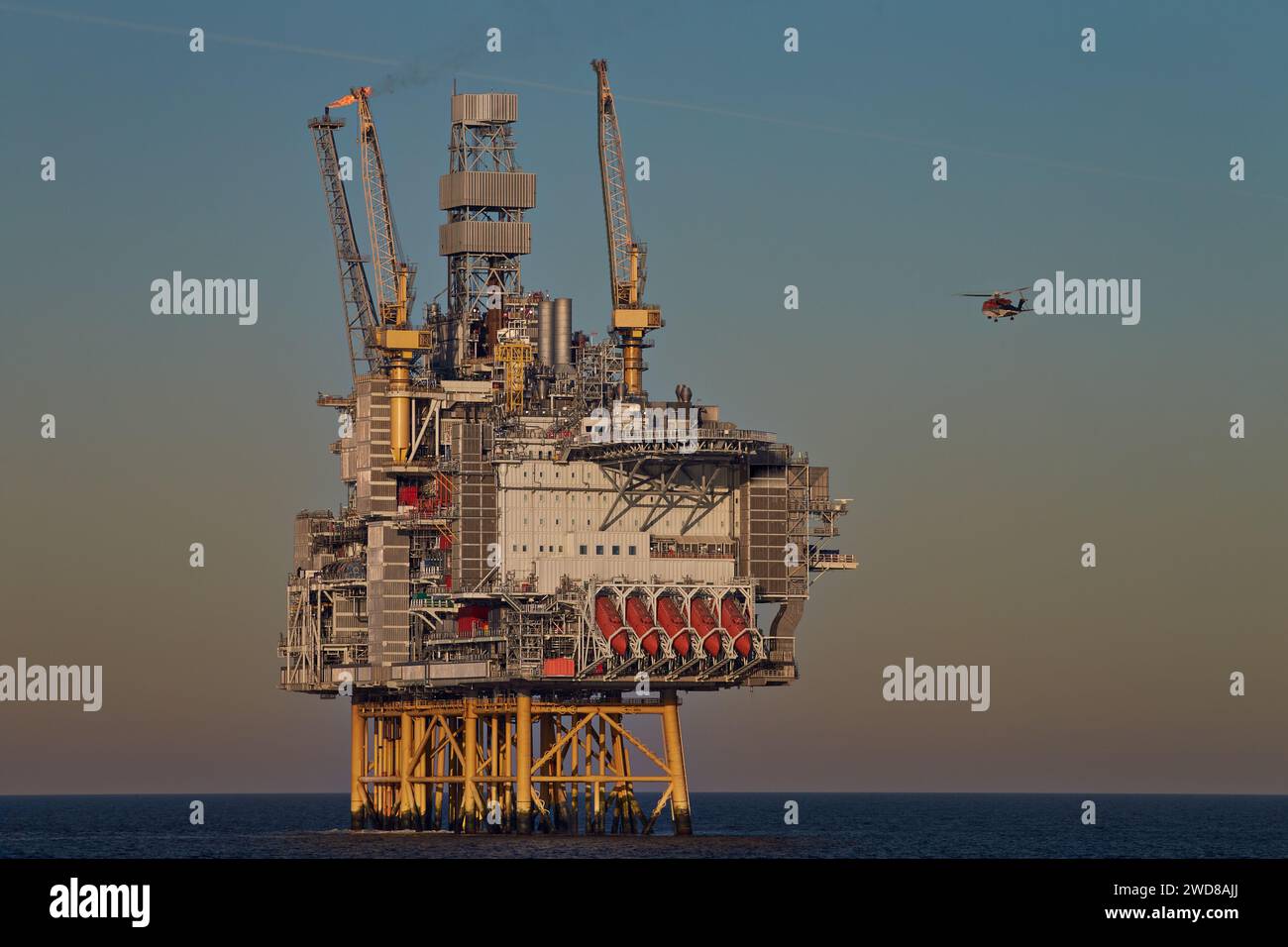 Helicopter flying towards jack up oil rig in the ocean for landing, on ...