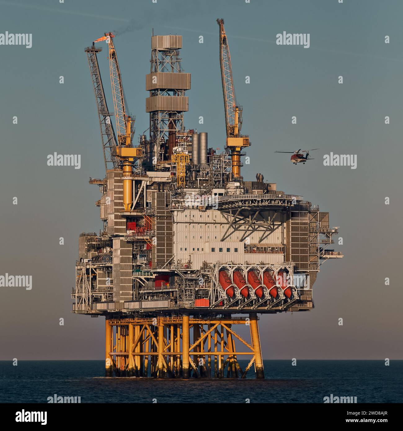 Helicopter landing on jack up oil rig in the ocean, on a clear sunny ...