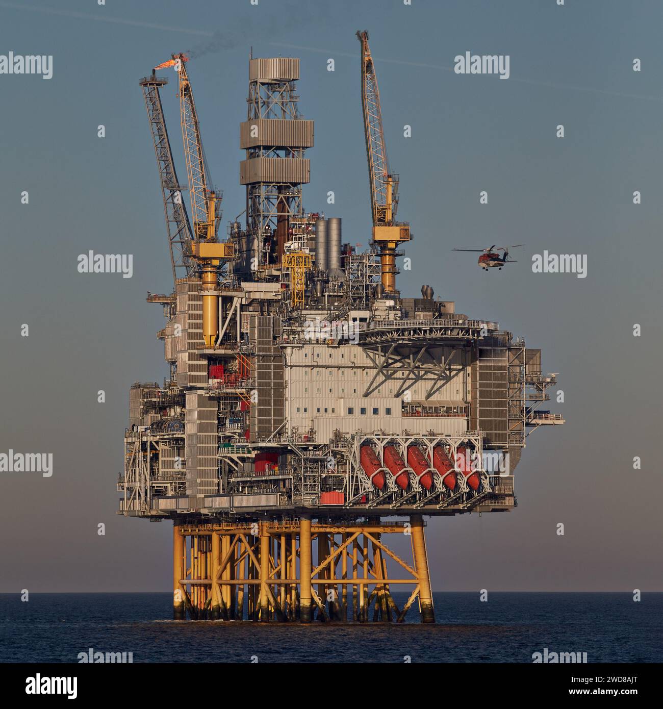 Helicopter landing on jack up oil rig in the ocean, on a clear sunny ...