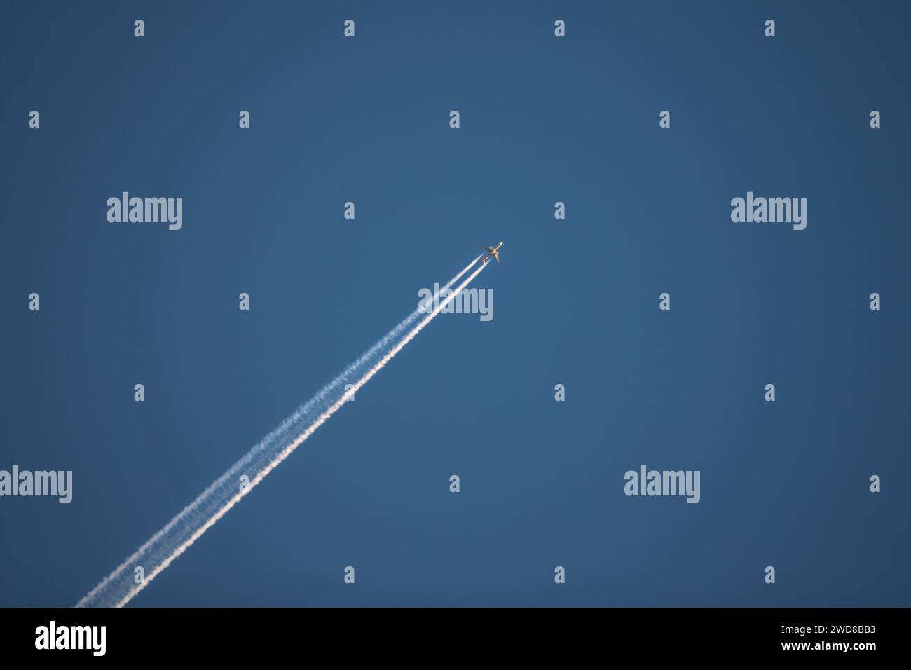 Photo of airplane flying diagonally in the clear blue sky, leaving ...