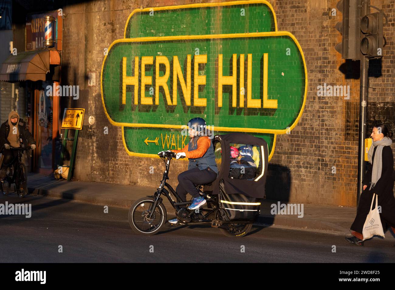 A cyclist with children loaded in the rear of her bike crosses the road ...