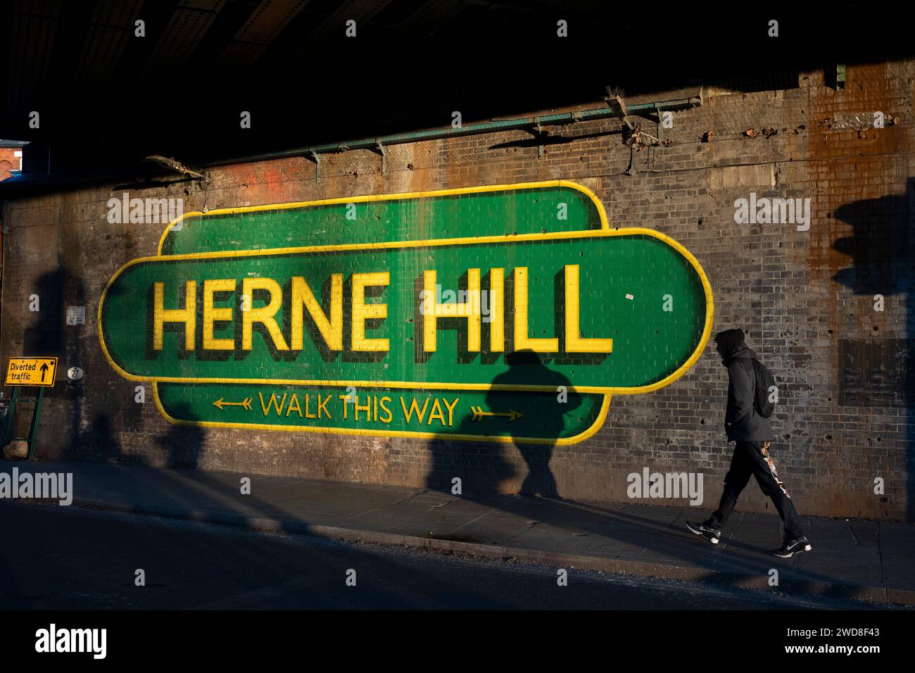 A Londoner and his shadow with the signage beneath the railway bridge ...