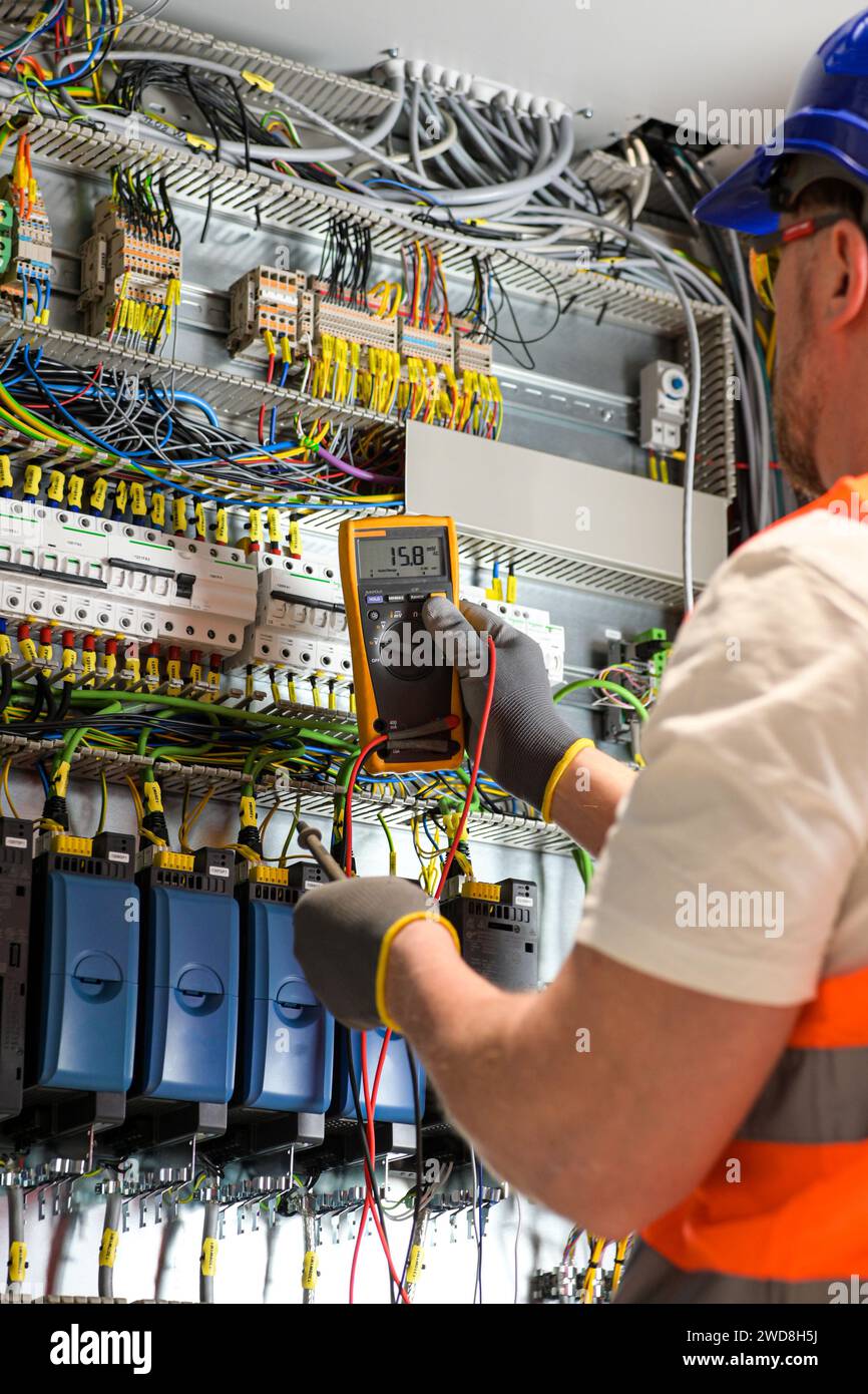 an electrician in a blue helmet, yellow glasses and an orange vest ...