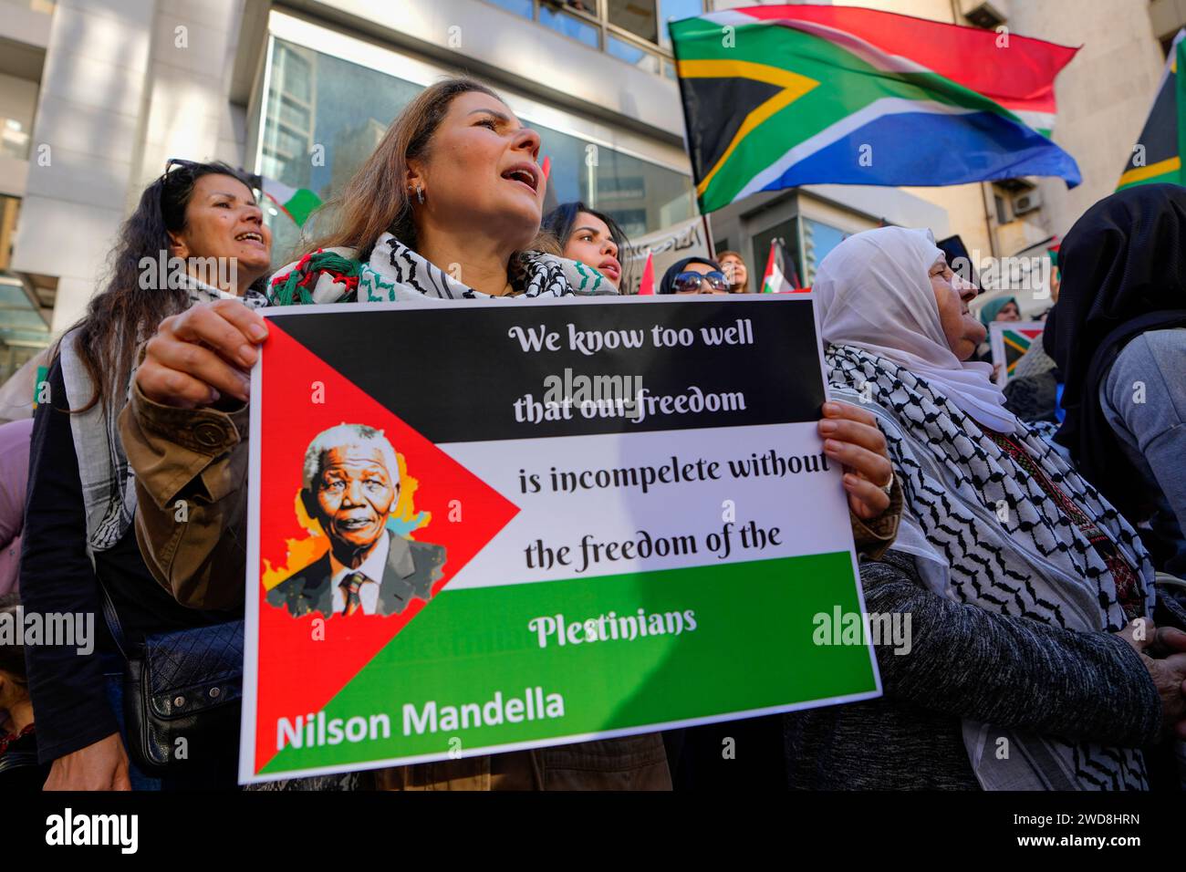 A woman holds a Palestinian flag with a Picture of former South Africa ...