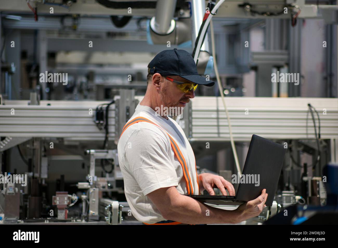 engineer in white t-shirt programming robot on assembly line using ...