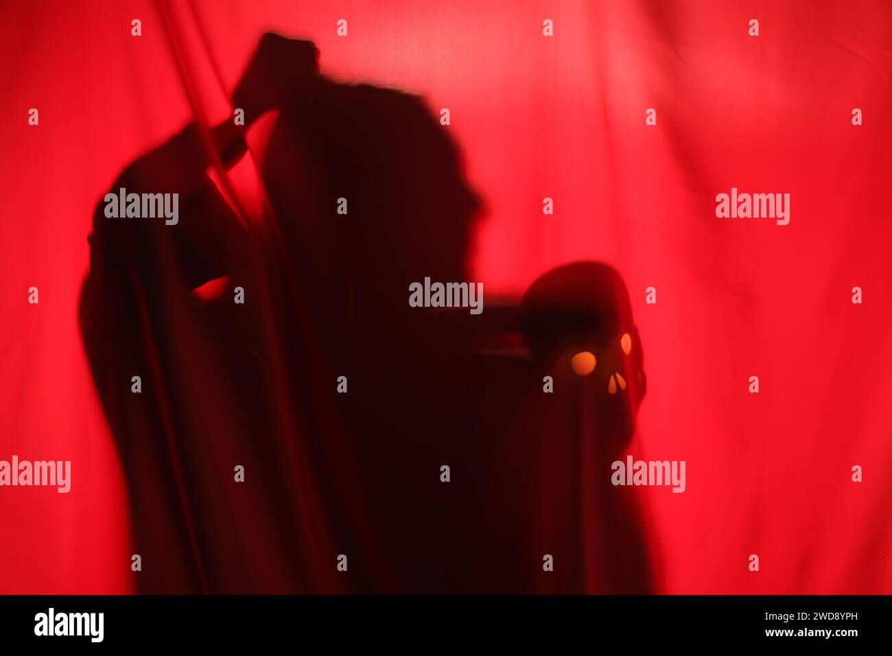 Silhouette of creepy ghost with skull behind red cloth, space for text ...