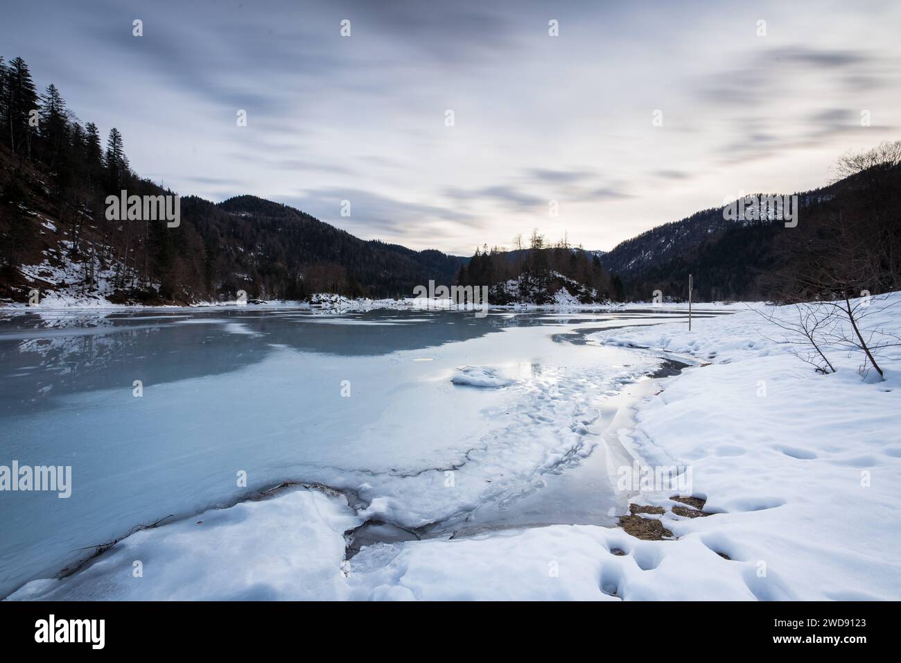 a frozen body of water surrounded by trees and snow covered ground ...