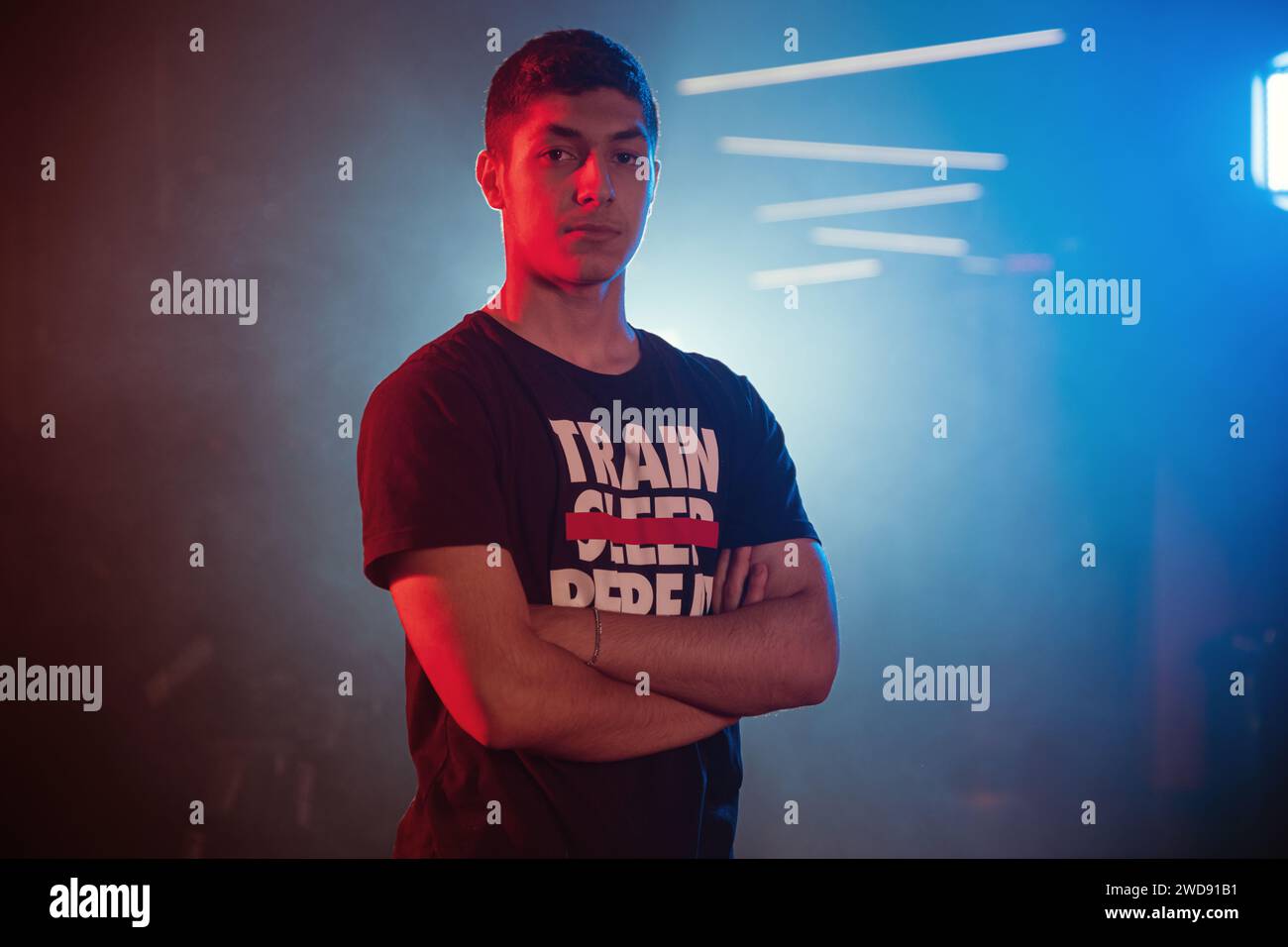 Portrait of a male athlete crossing his arms in a gym, highlighted by ...