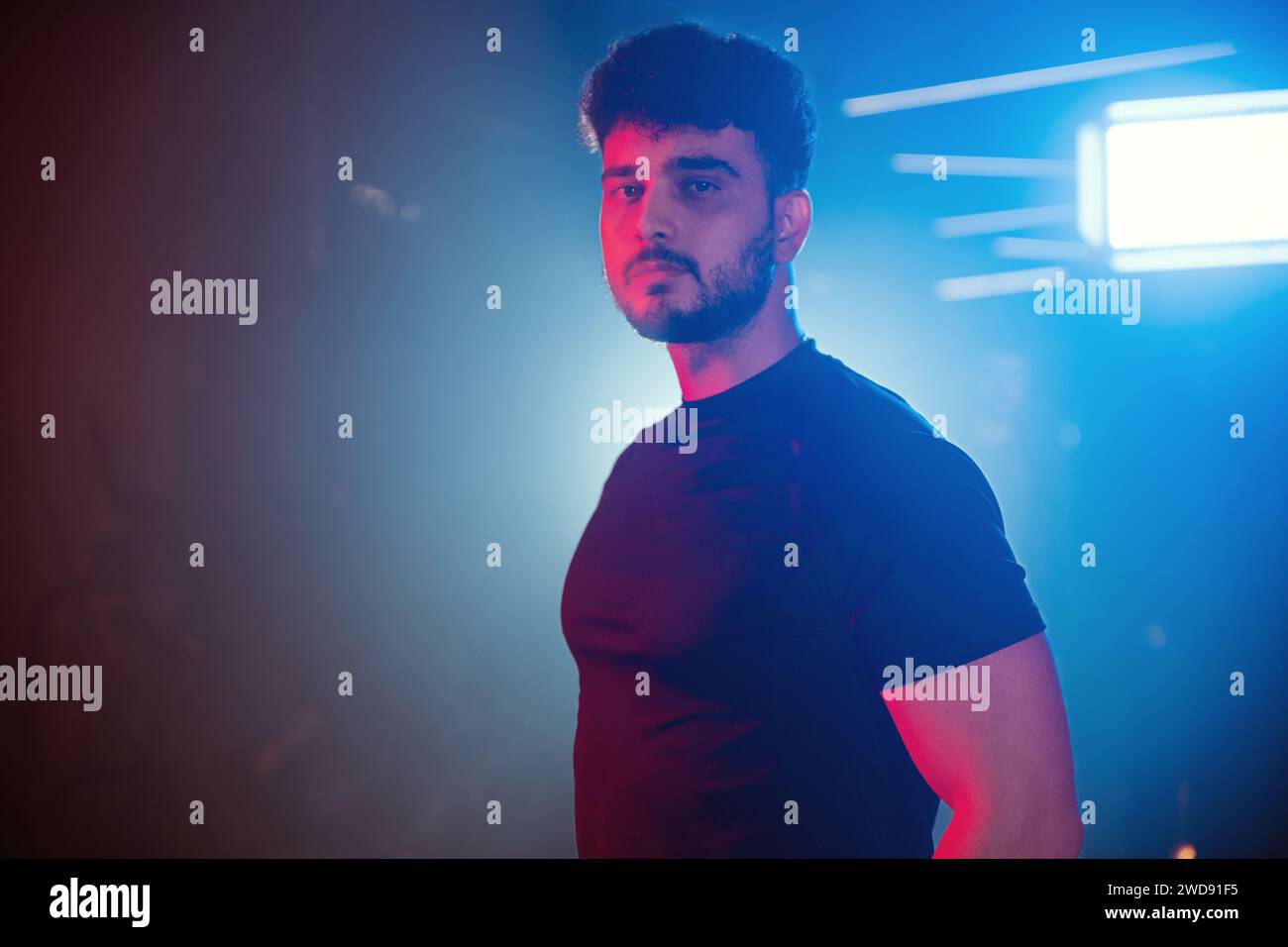 Portrait of a male athlete a gym, highlighted by blue and red lights ...