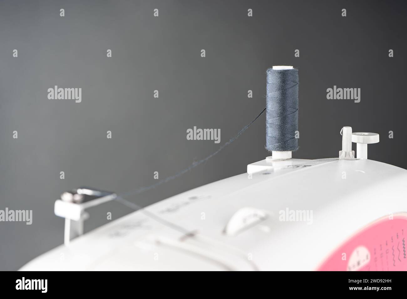 Spool of gray sewing thread stands on top of a white modern sewing ...