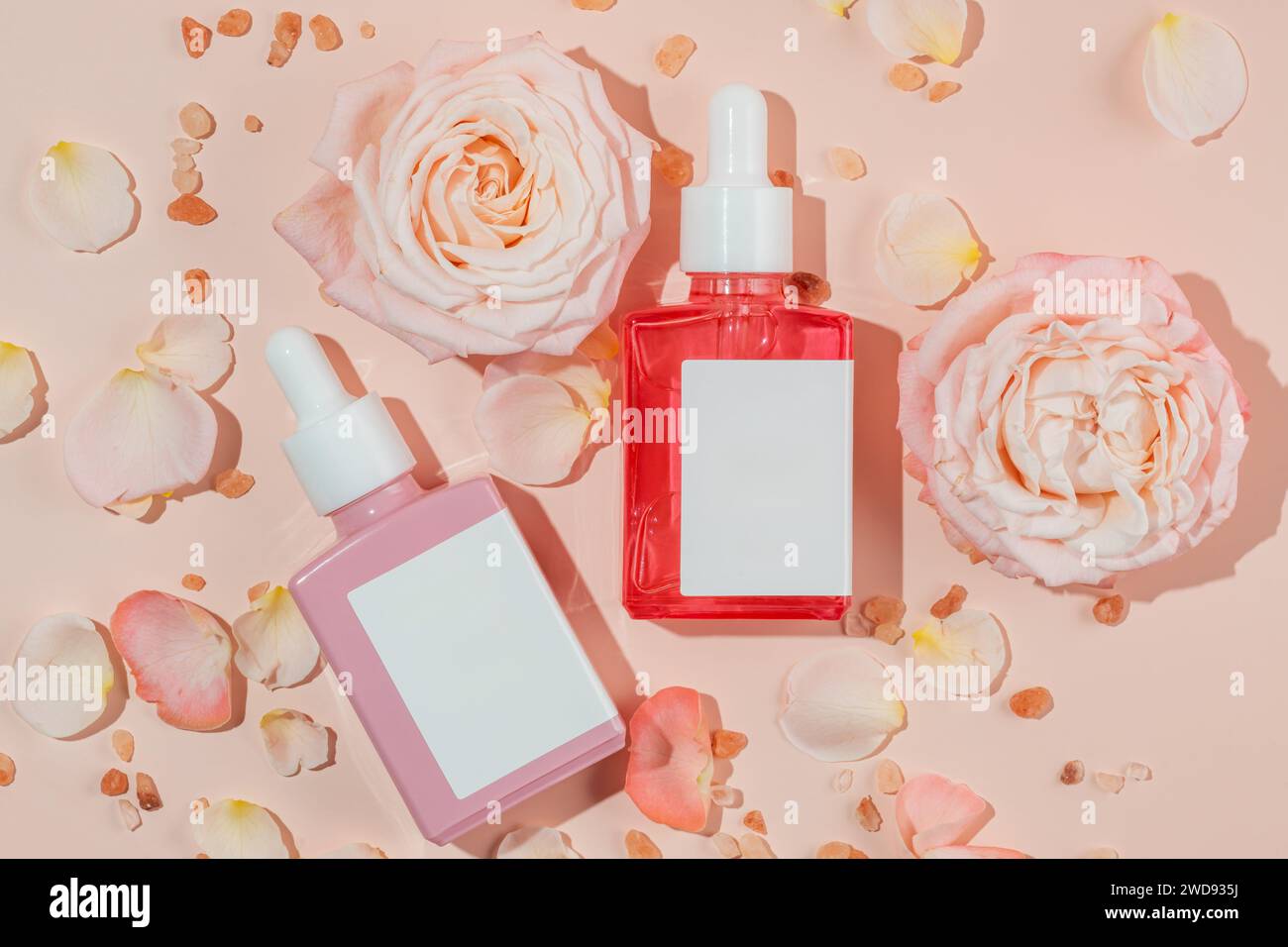 Bottles of essential rose oil and flowers on peach background. Flat lay ...