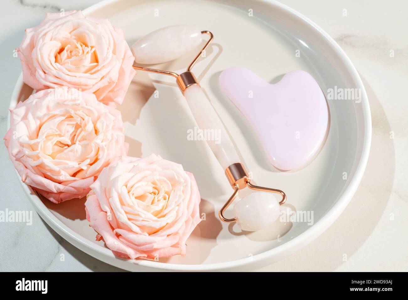 Jade face roller for beauty facial massage therapy. Flat lay on ceramic ...