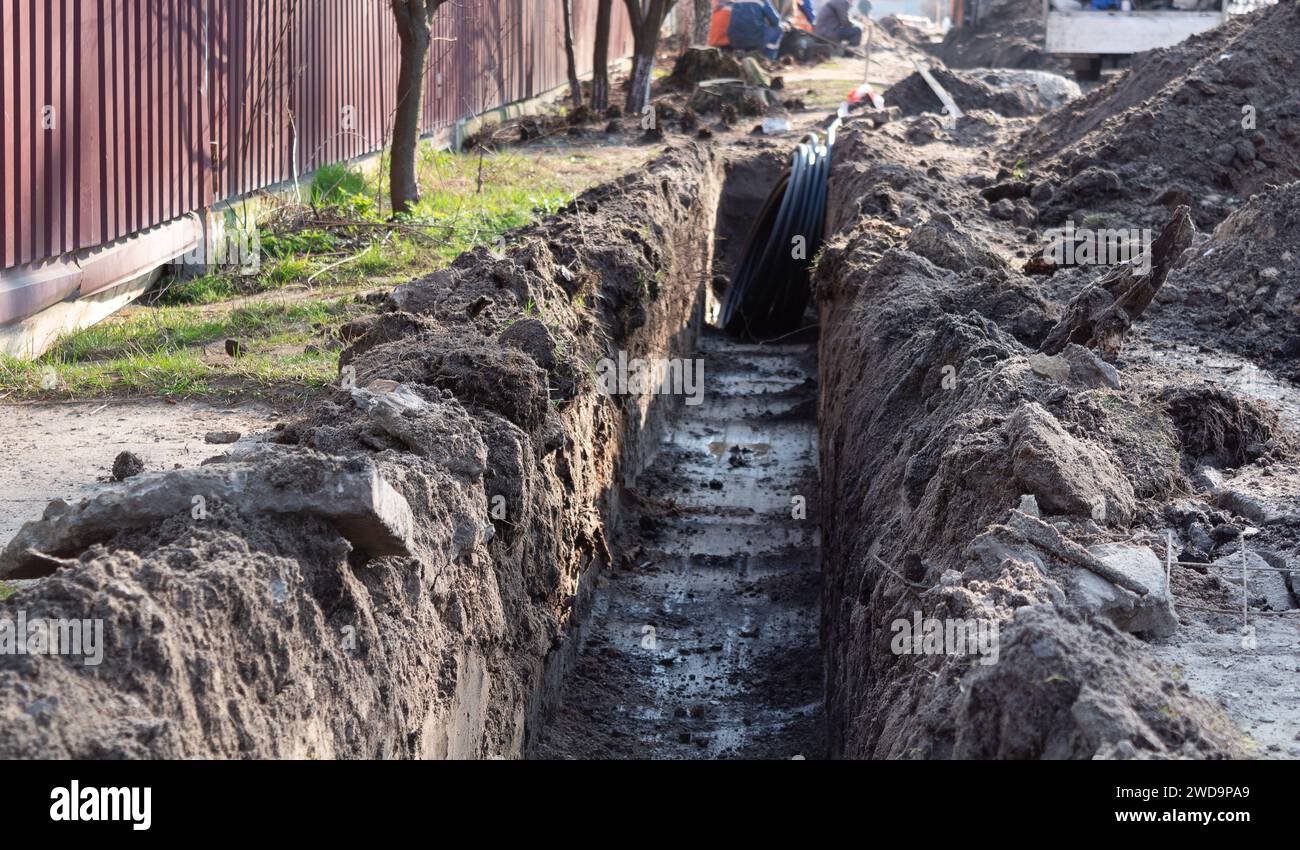 Earthwork. A deep long trench dug in the ground for laying cables, pipes. Telecommunications ...