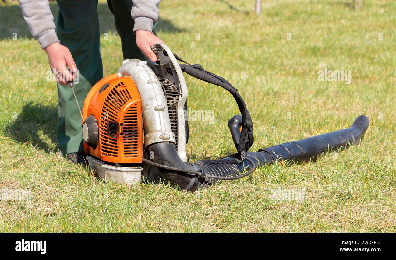 The gardener starts a gasoline lawn blower. Garden and lawn care ...