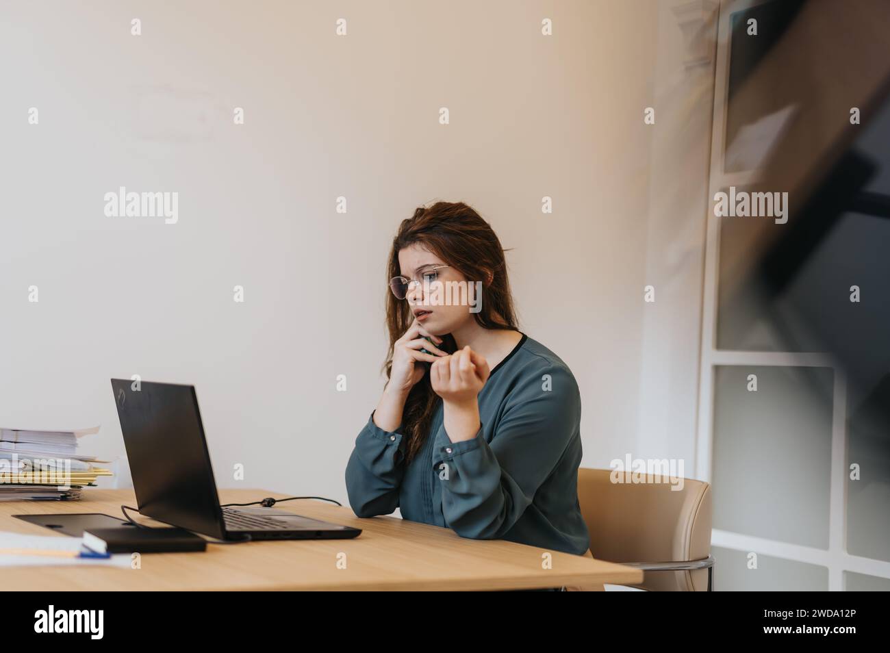 Woman looks confused during phone call while working on the lap top at ...