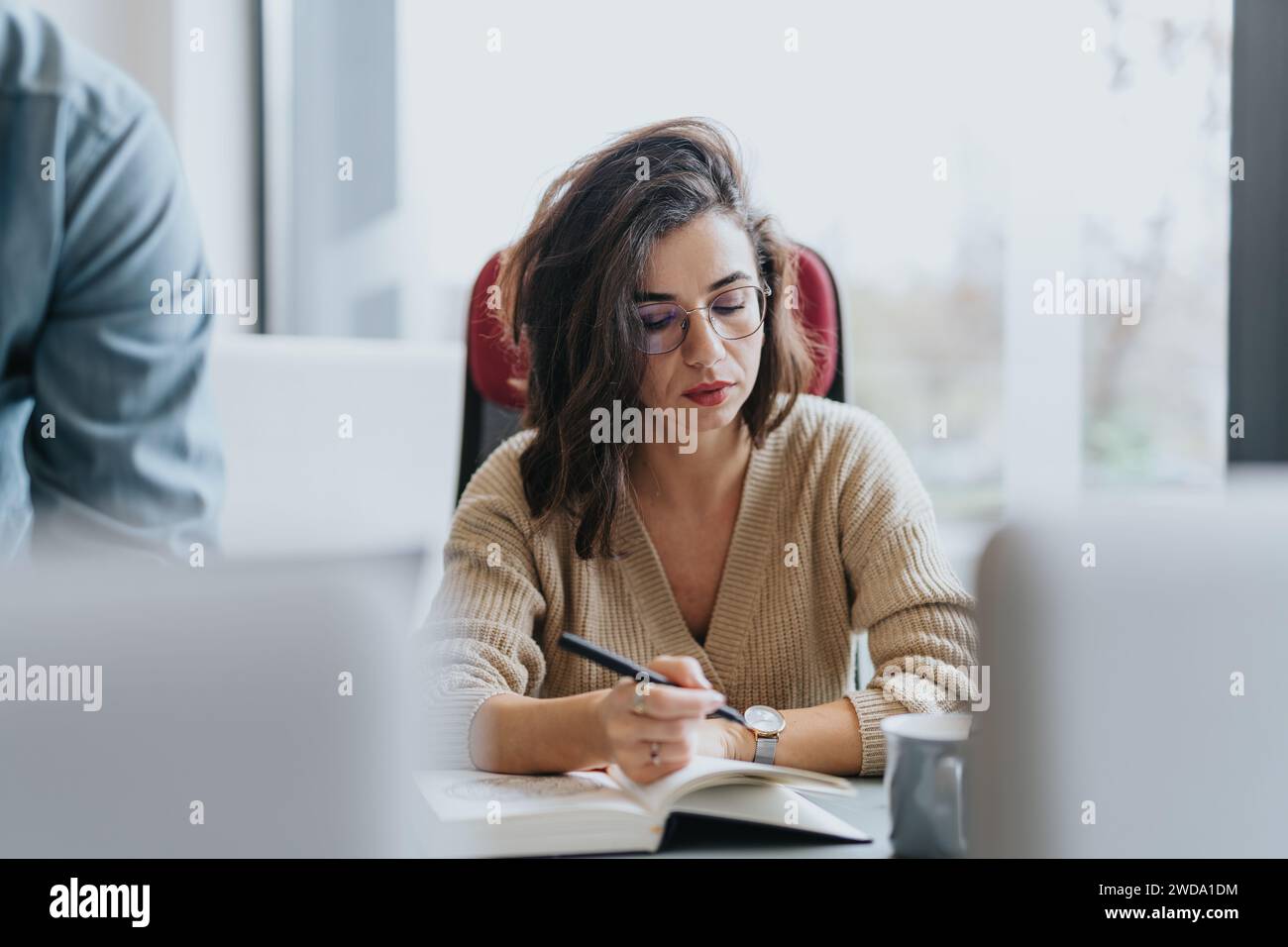 Stunning, middle-aged woman writing statistics, business ideas or sales growth while sitting in ...