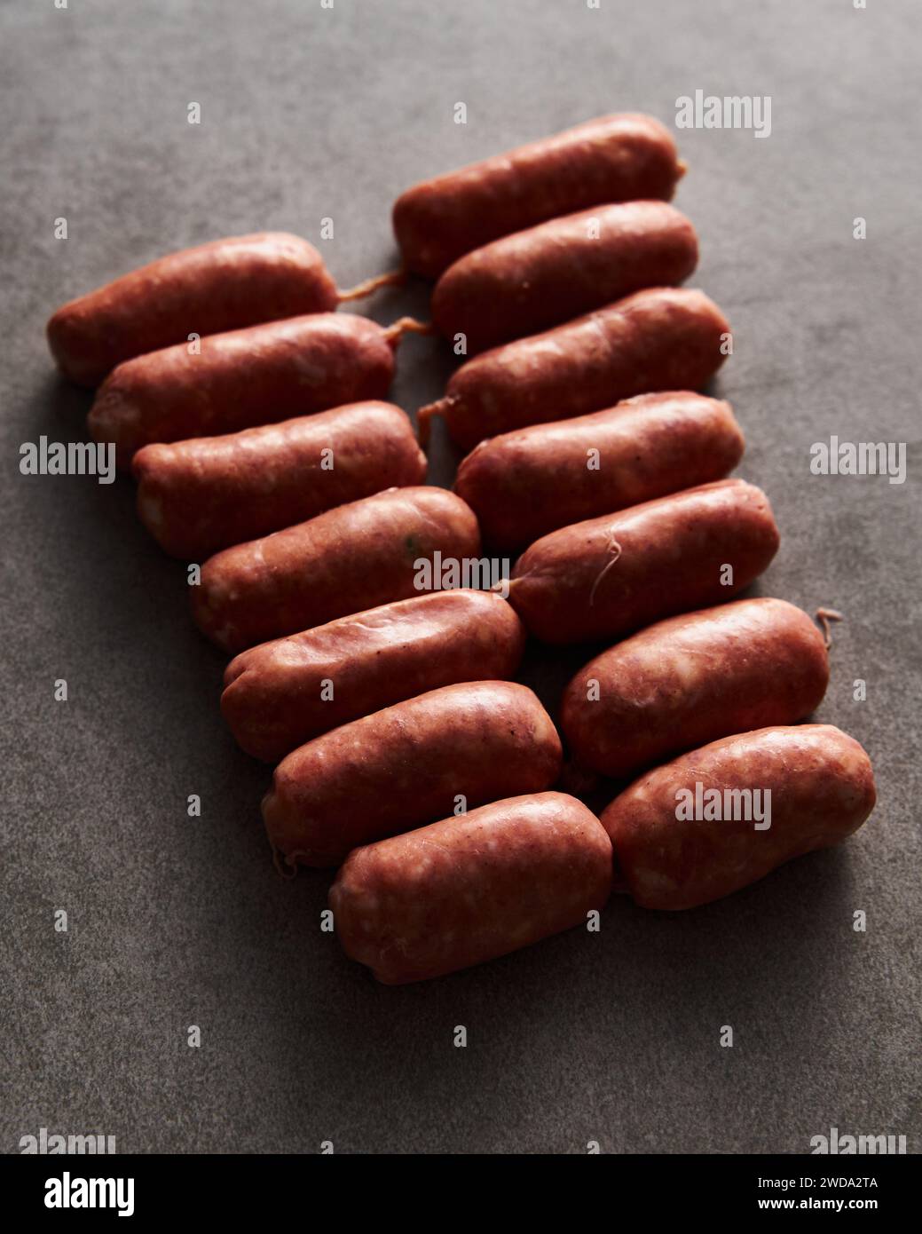 Mini pork sausages on grey concrete background, loft style. Raw and ...