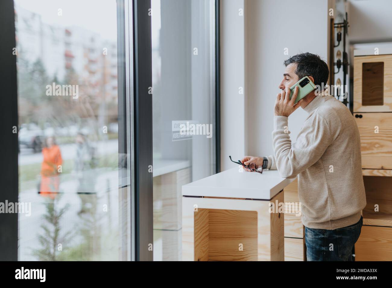 Standing in the contemporary office, the businessman engages in a phone ...