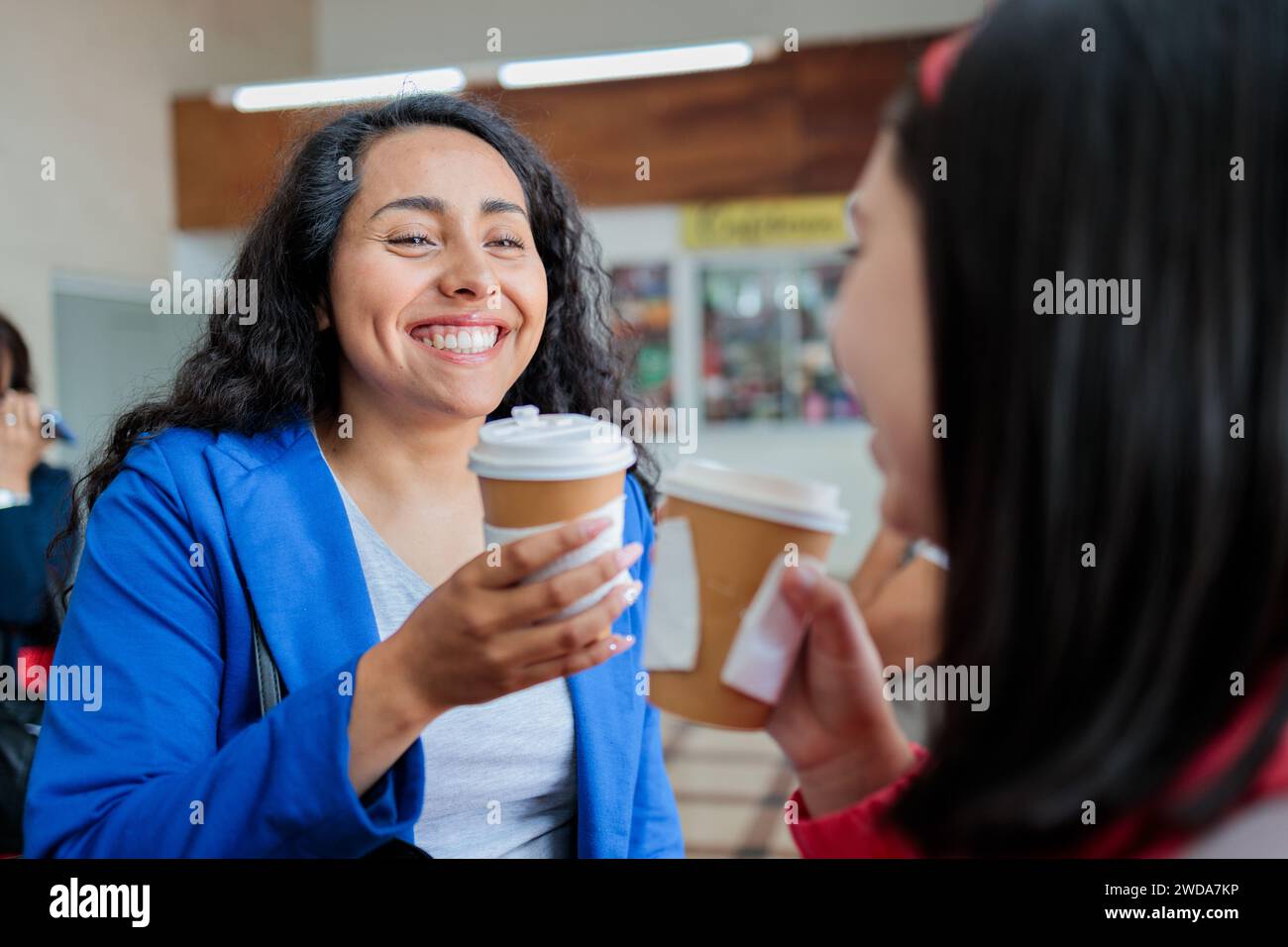 Two young smiling latin women commuters waiting for public train ...