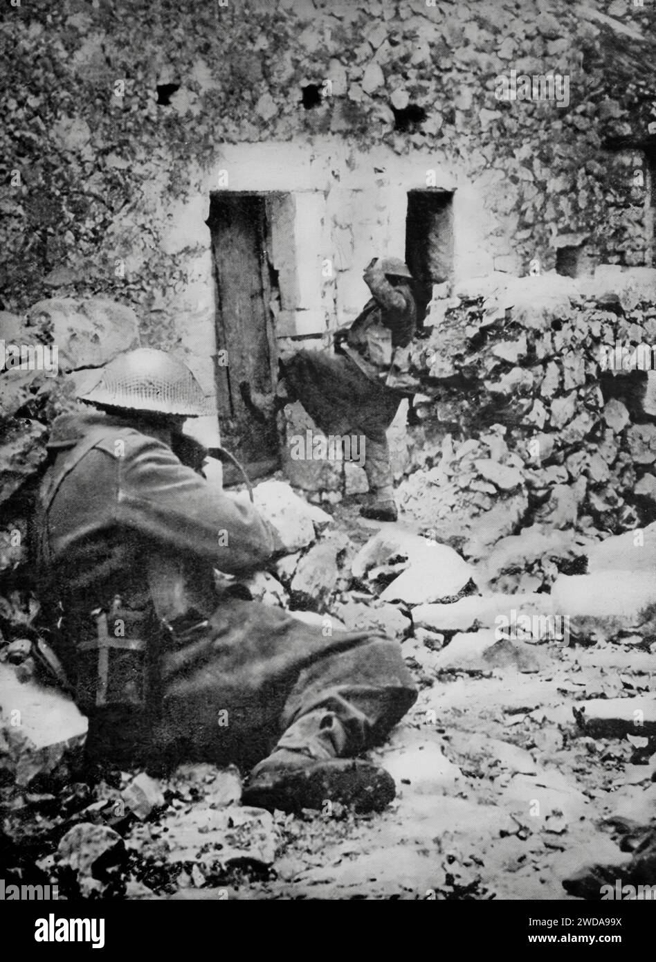 A British soldier kicking open a door during the invasion of Italy in ...