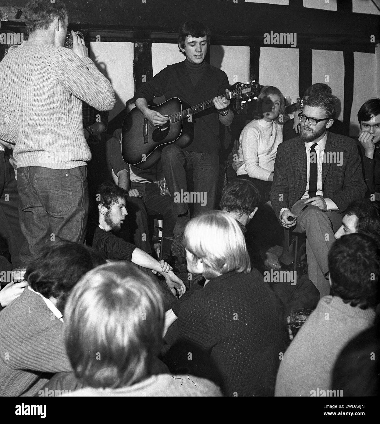 1960s, historical, folk jam session in a pub, a young man playing his ...