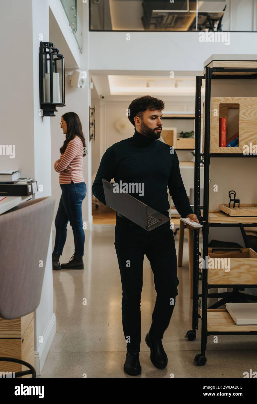 A front view shot of male employee changing working area, carrying lap ...