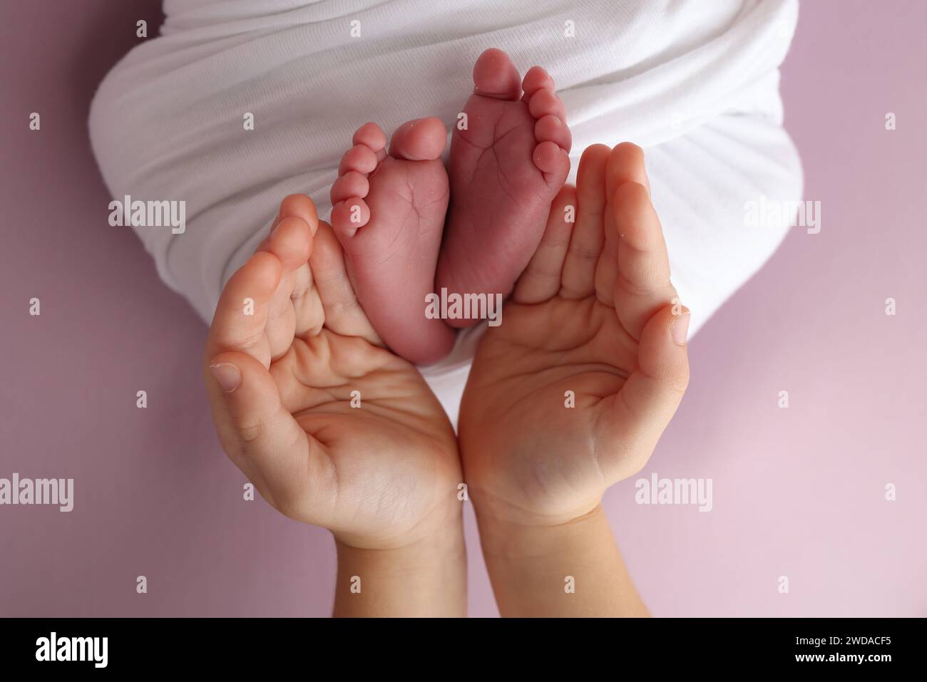 The palms of the father, the mother are holding the foot of the newborn ...