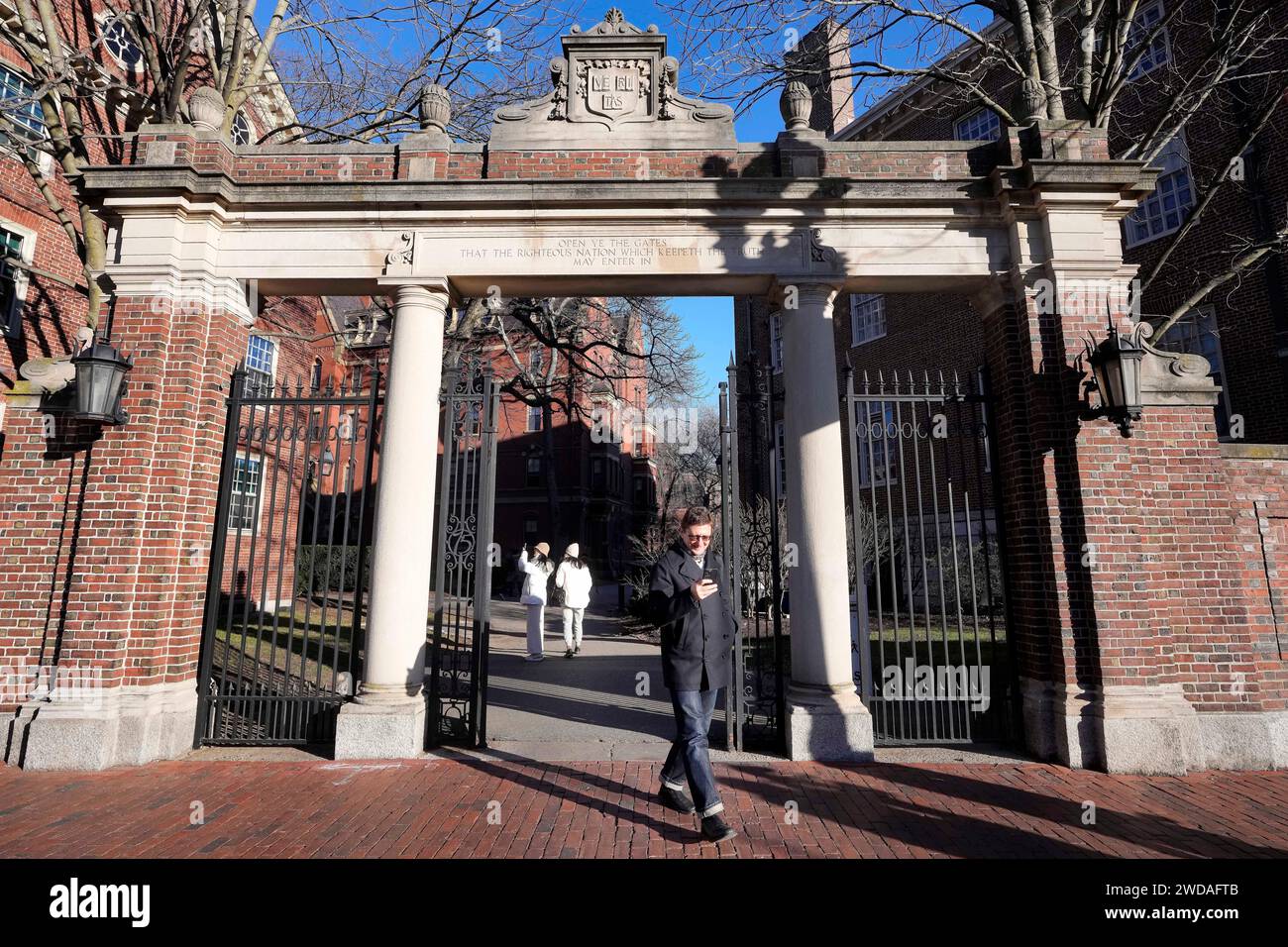 FILE - A passer-by walks through a gate to the Harvard University ...