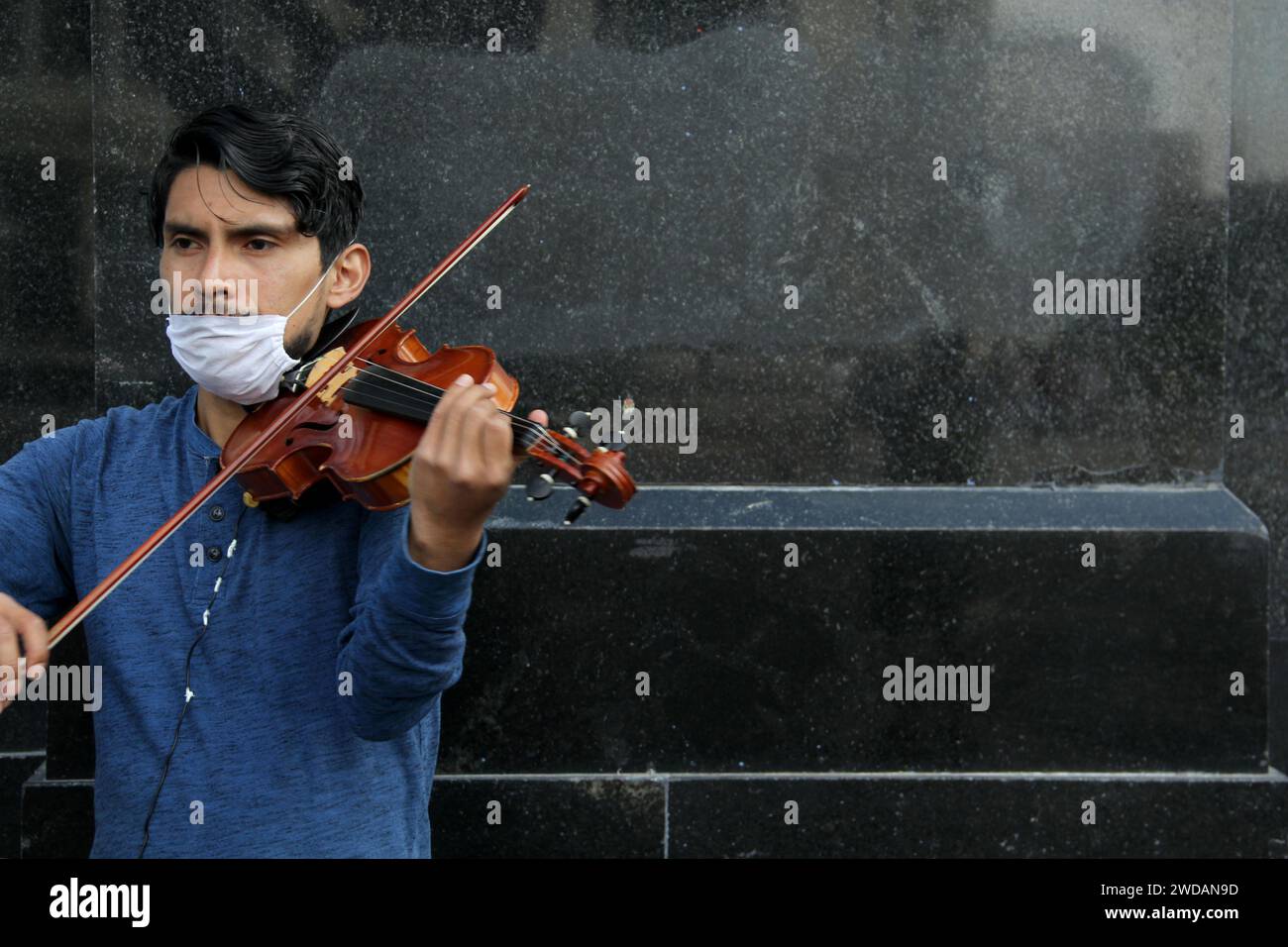 Latin man with protection mask playing musical instrument violin in the ...