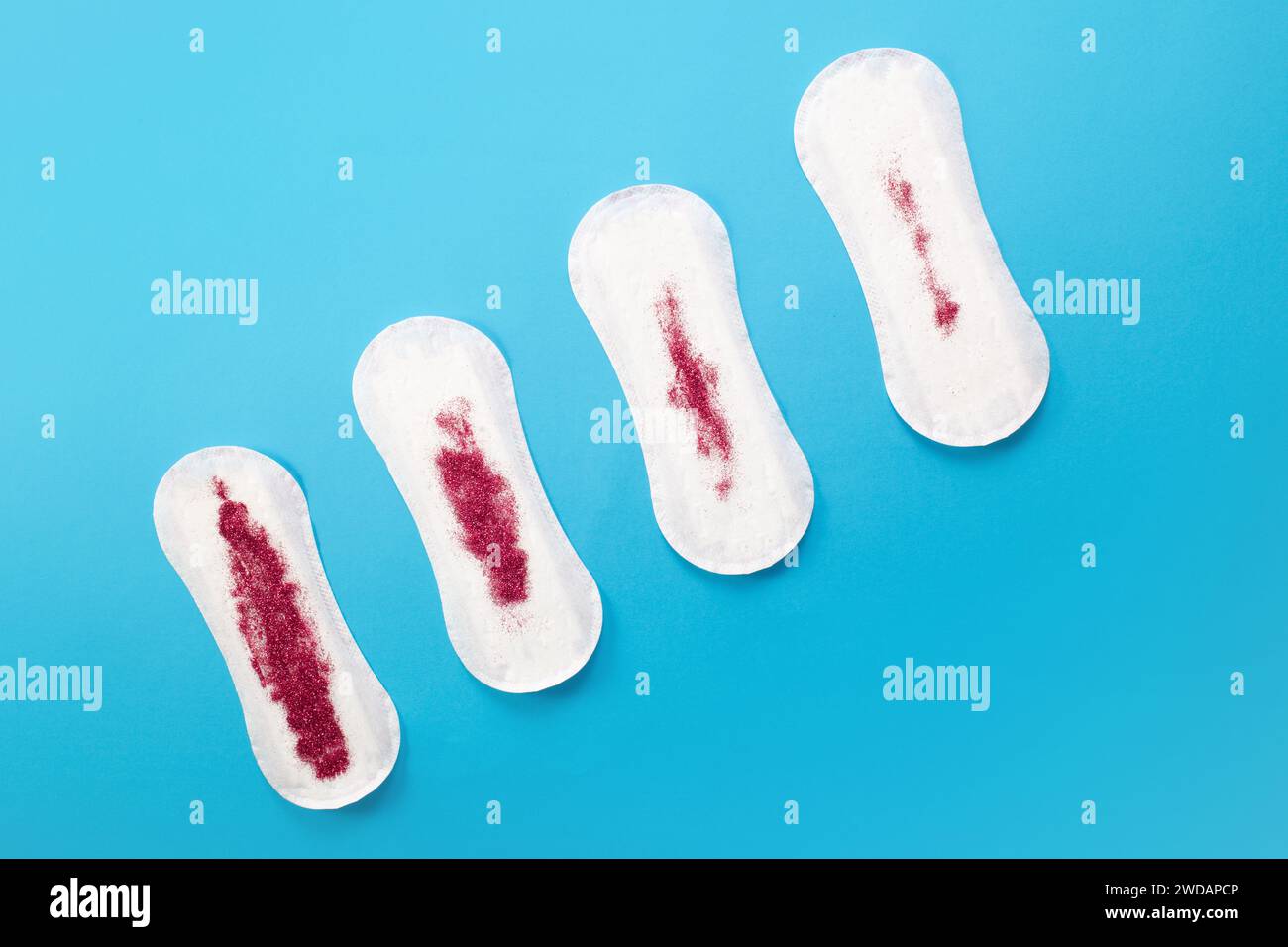 Feminine hygiene pads with red glitter on blue background. First ...
