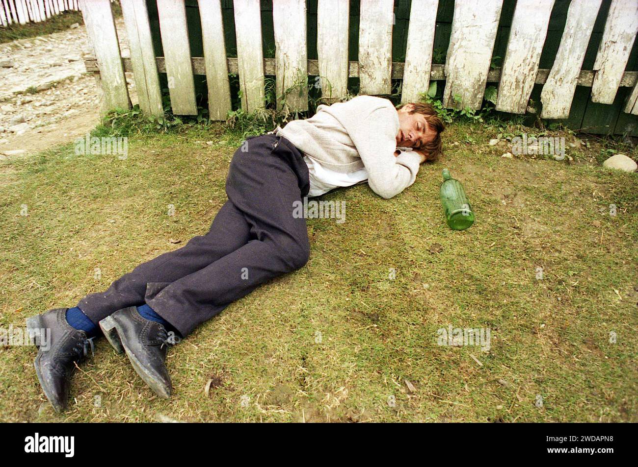 Romania, approx. 1992. A drunk young man sleeping by a village lane ...
