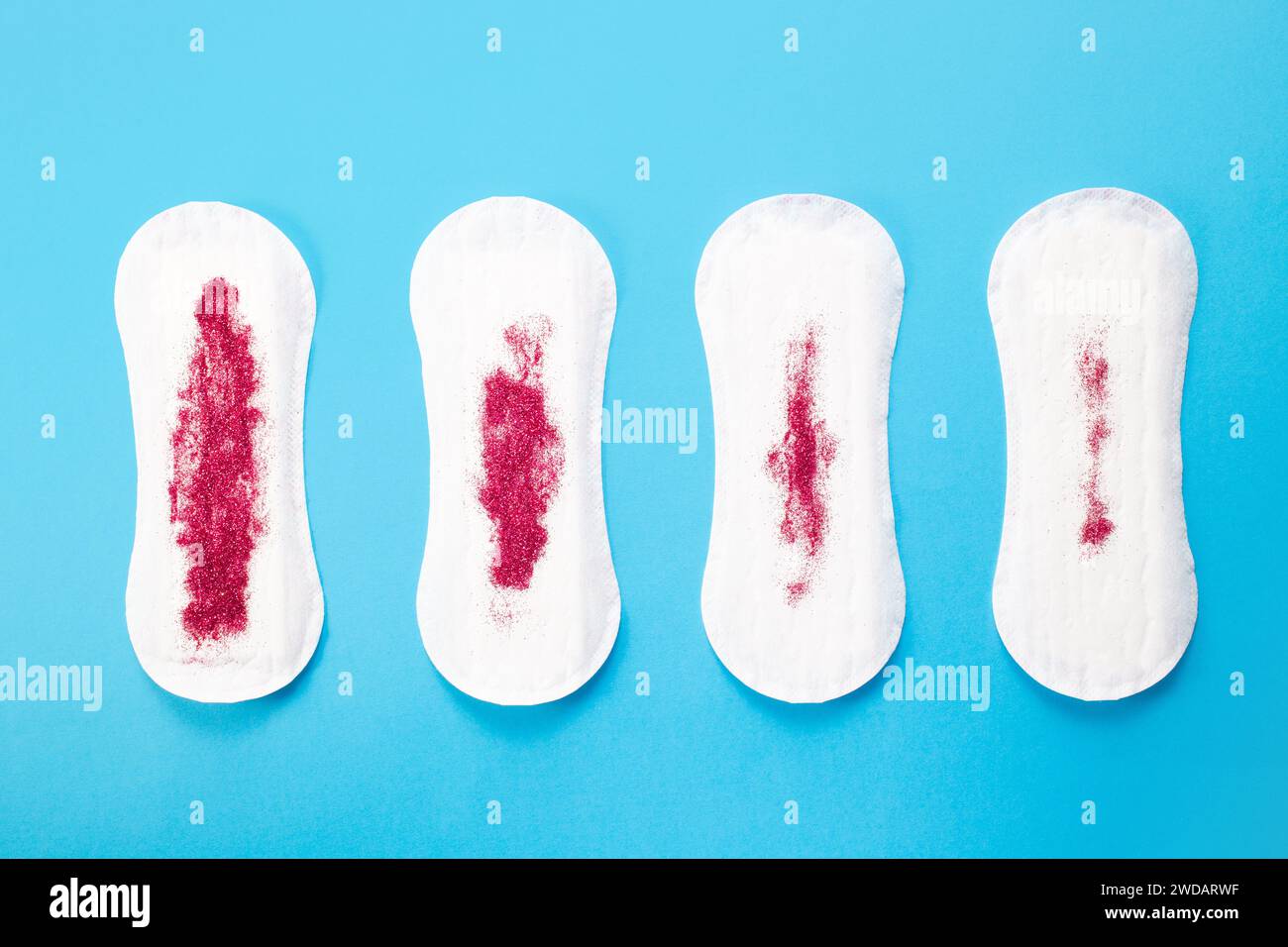 Feminine hygiene pads with red glitter on blue background. First ...