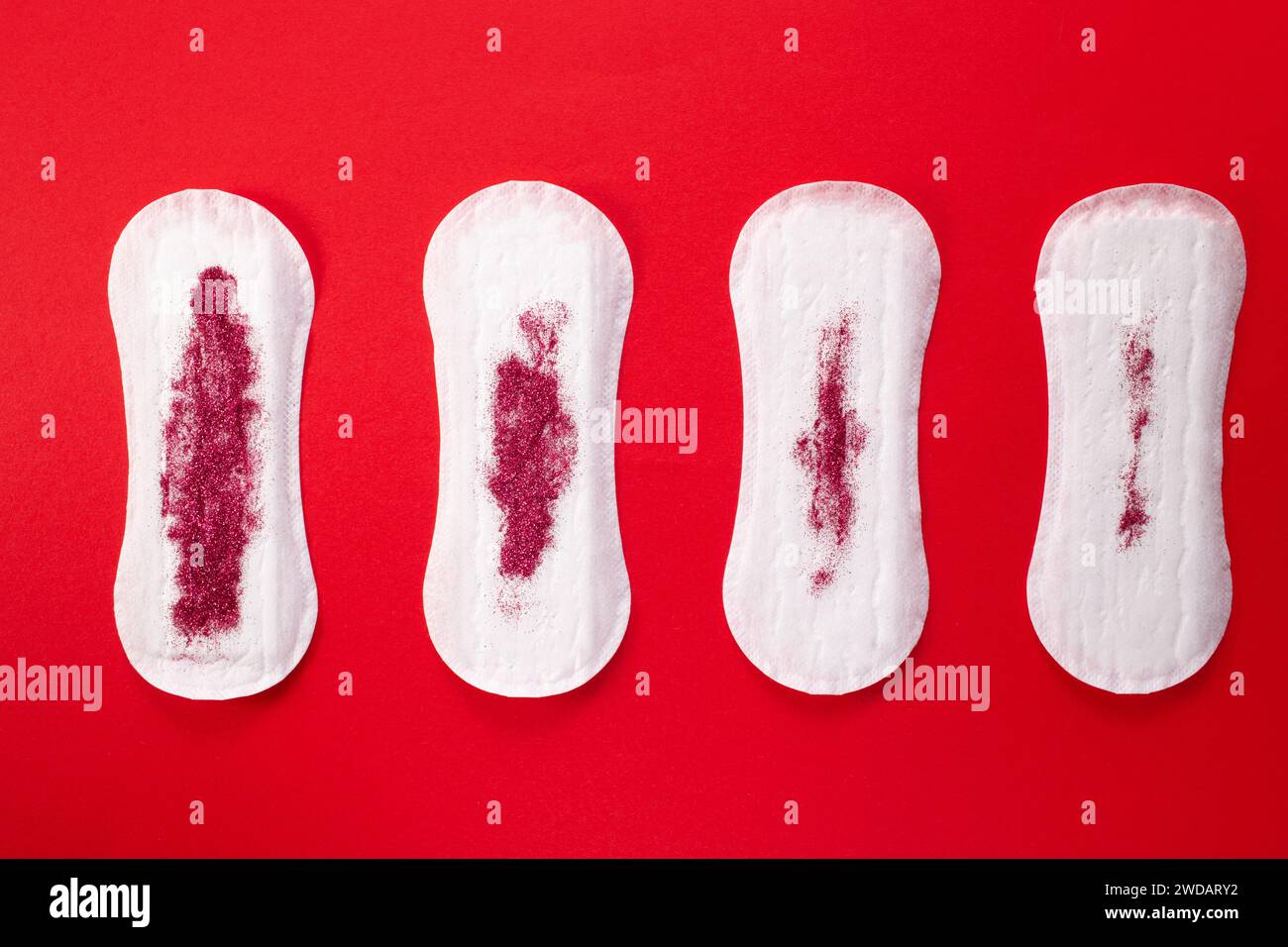 Feminine hygiene pads with red glitter on red background. First ...