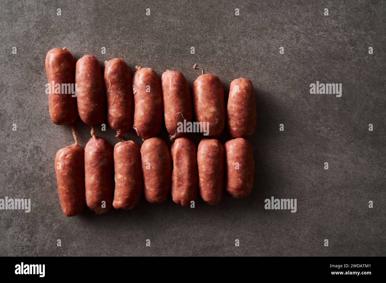 Mini pork sausages on grey concrete background, loft style. Raw and ...