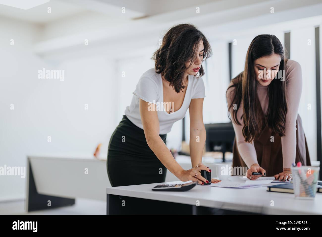 Two women collaborating over documents in a bright office setting ...