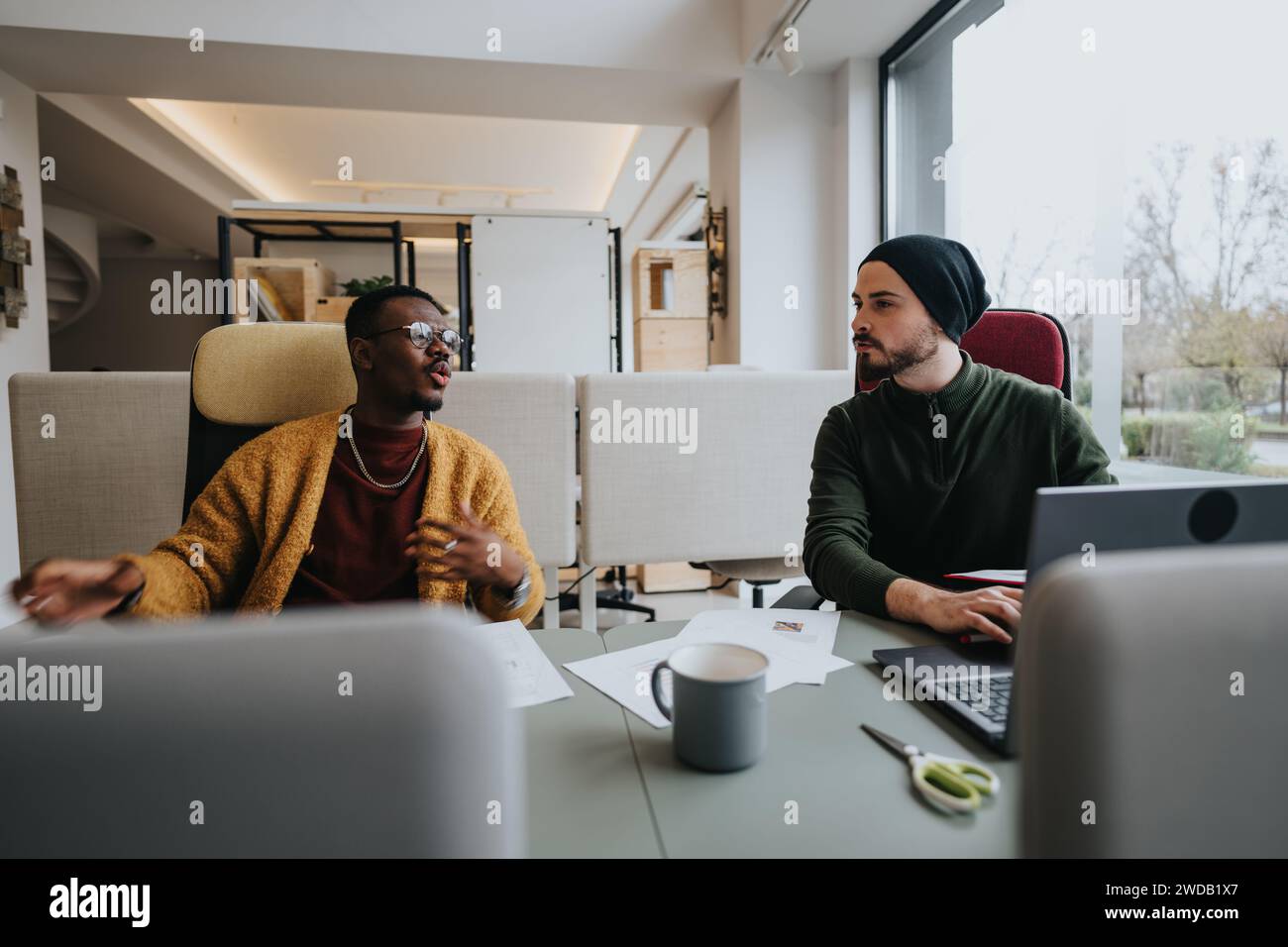 Two diverse male colleagues in a modern office engage in a productive ...